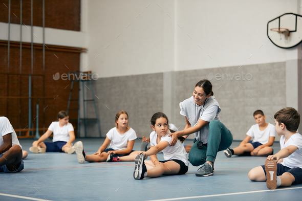 Happy female PE teacher having a class with group of elementary students at school gym. Stock ...